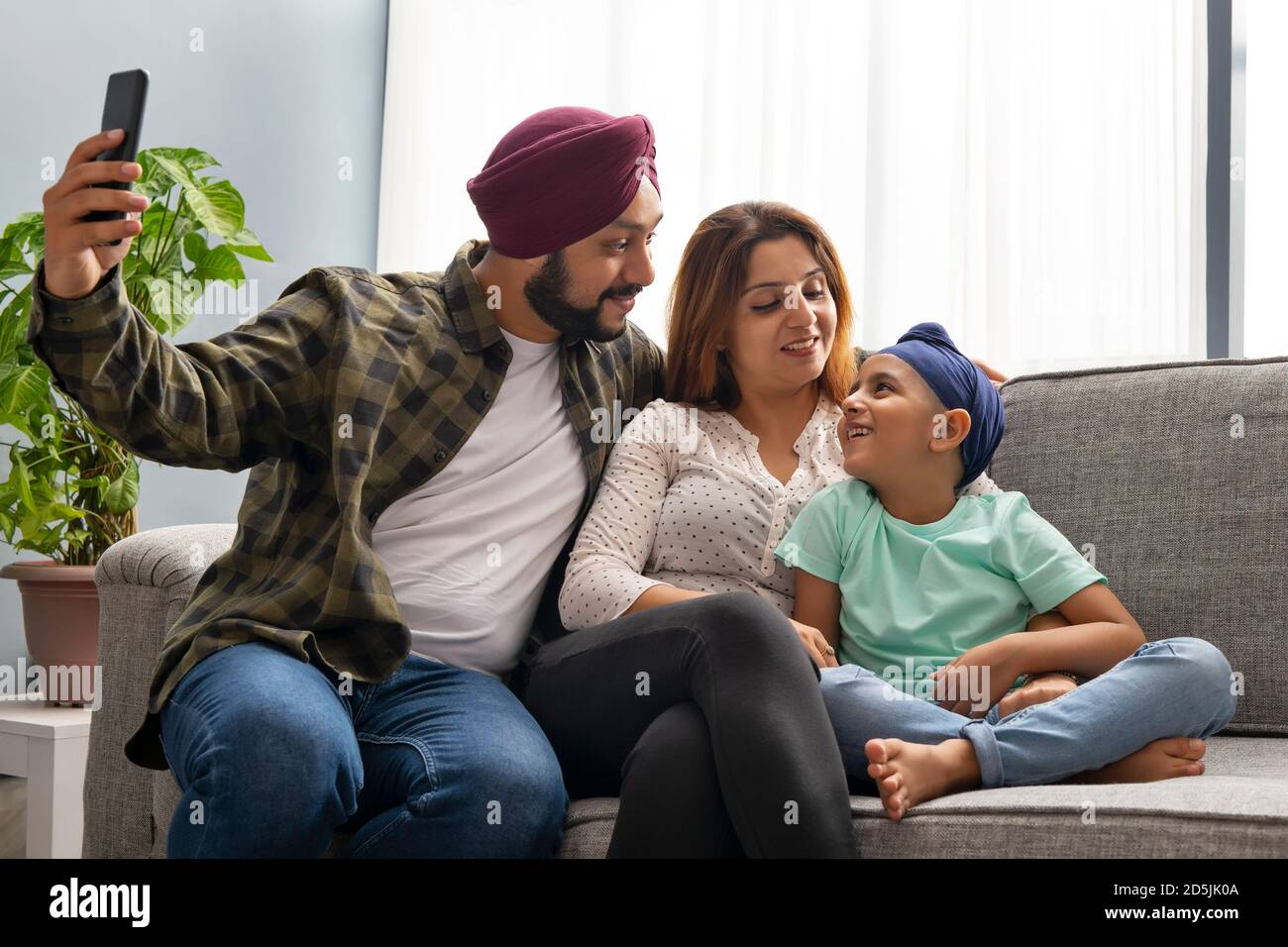 A SIKH FATHER AND MOTHER LOOKING AT SMILING SON WHILE TAKING A SELFIE ...
