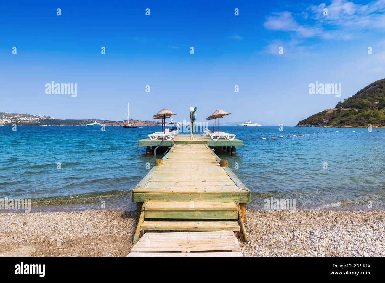 Beach pier with sun umbrellas and beach loungers in Mediterranean sea ...