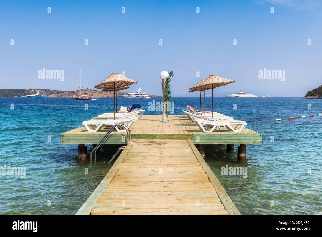 Beach pier with sun umbrellas and beach loungers in Mediterranean sea ...