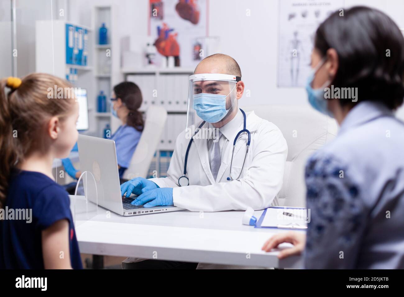 Child looking at doctor wearing face mask agasint coronavirus during ...