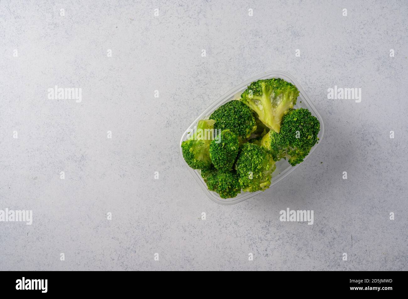 Frozen vegetables broccoli in a plastic tray on an gray background ...