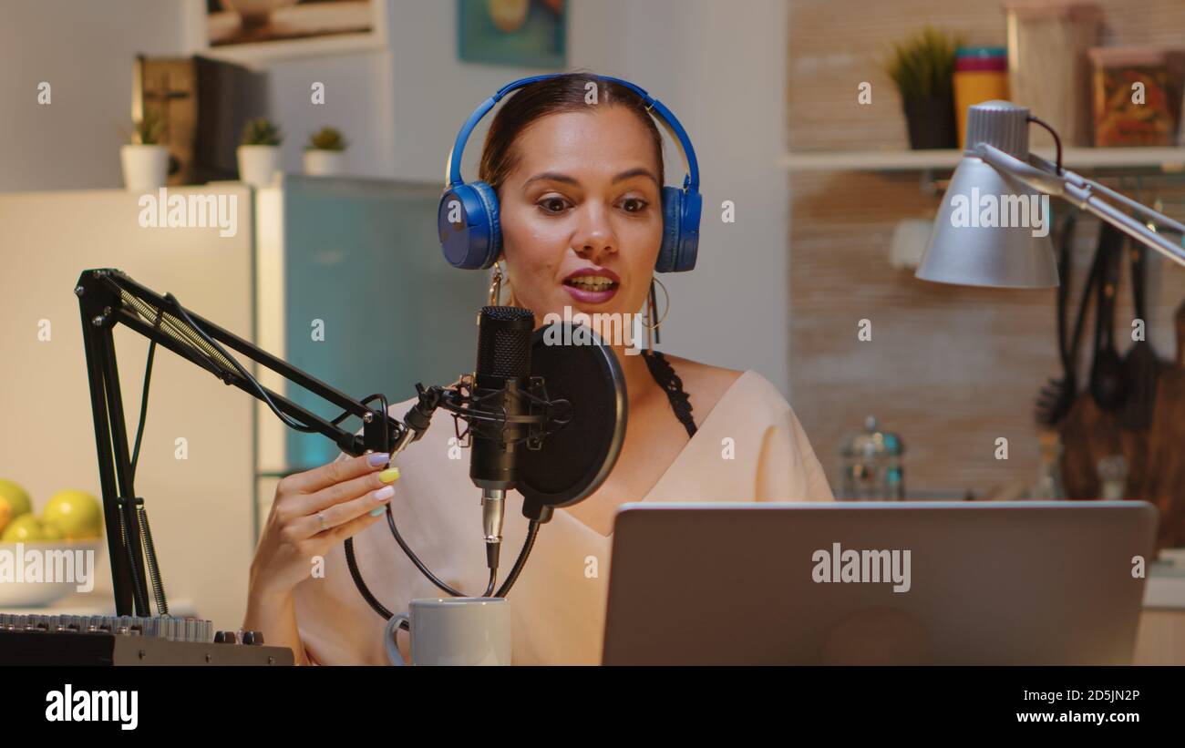 Creative influencer with headphones speaking with fans during live on ...