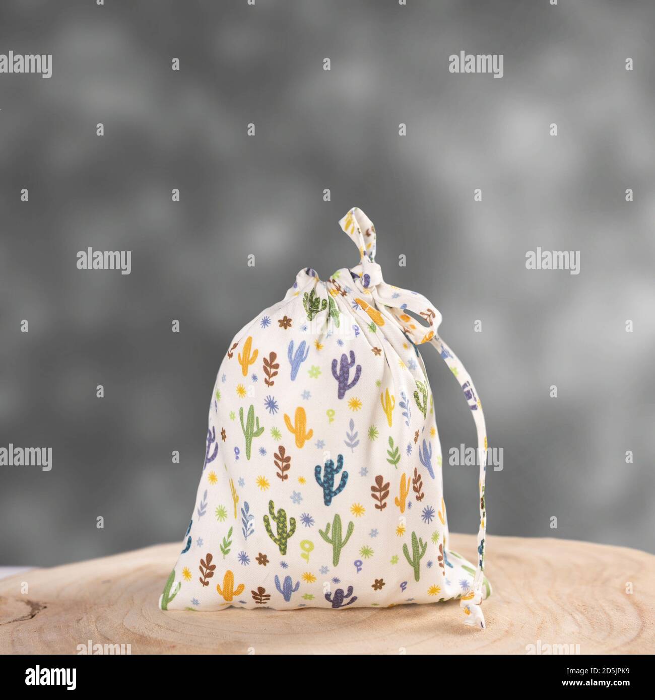 Small hygiene draw-string bag with colorful print displayed on a wooden ...