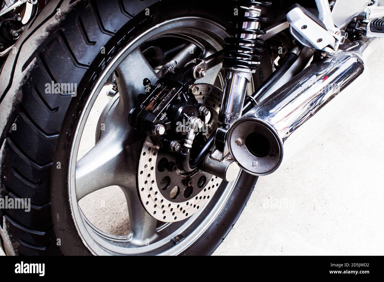 The back of sports bike close-up in garage. Wheel, brake disc, exhaust ...