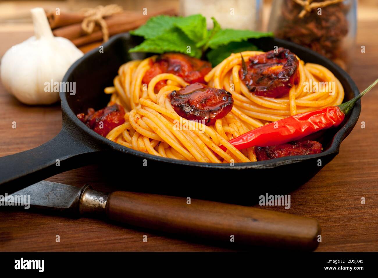 italian spaghetti pasta and tomato with mint leaves on iron skillet ...