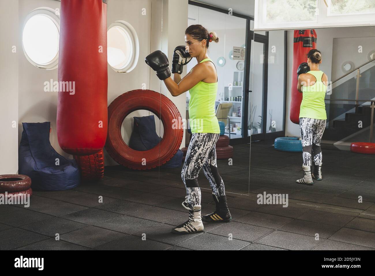 Young female trains in the gym and do boxing exercises in boxing gloves ...