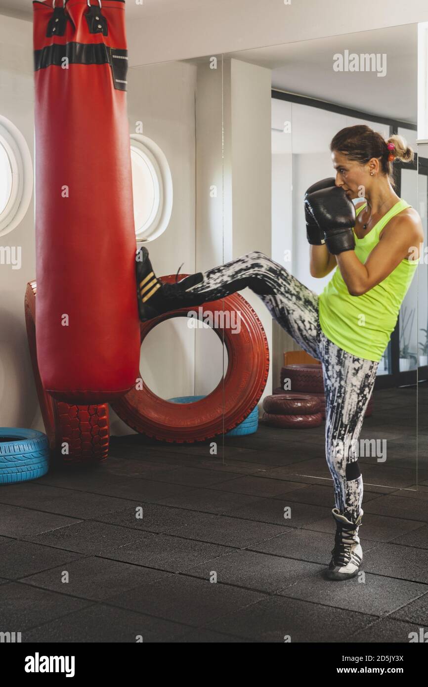 Young female trains in the gym and do boxing exercises in boxing gloves ...