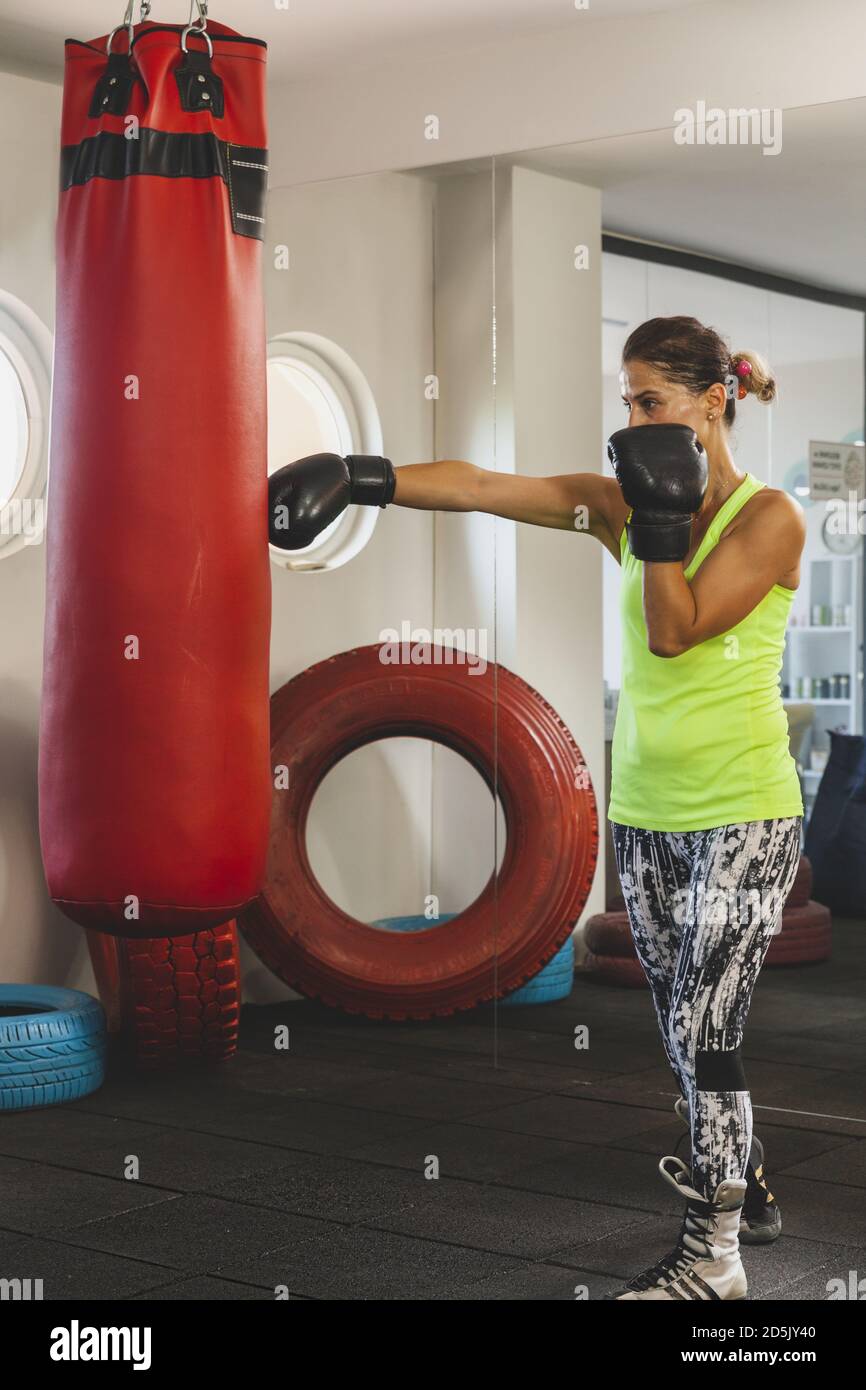 Young female trains in the gym and do boxing exercises in boxing gloves ...