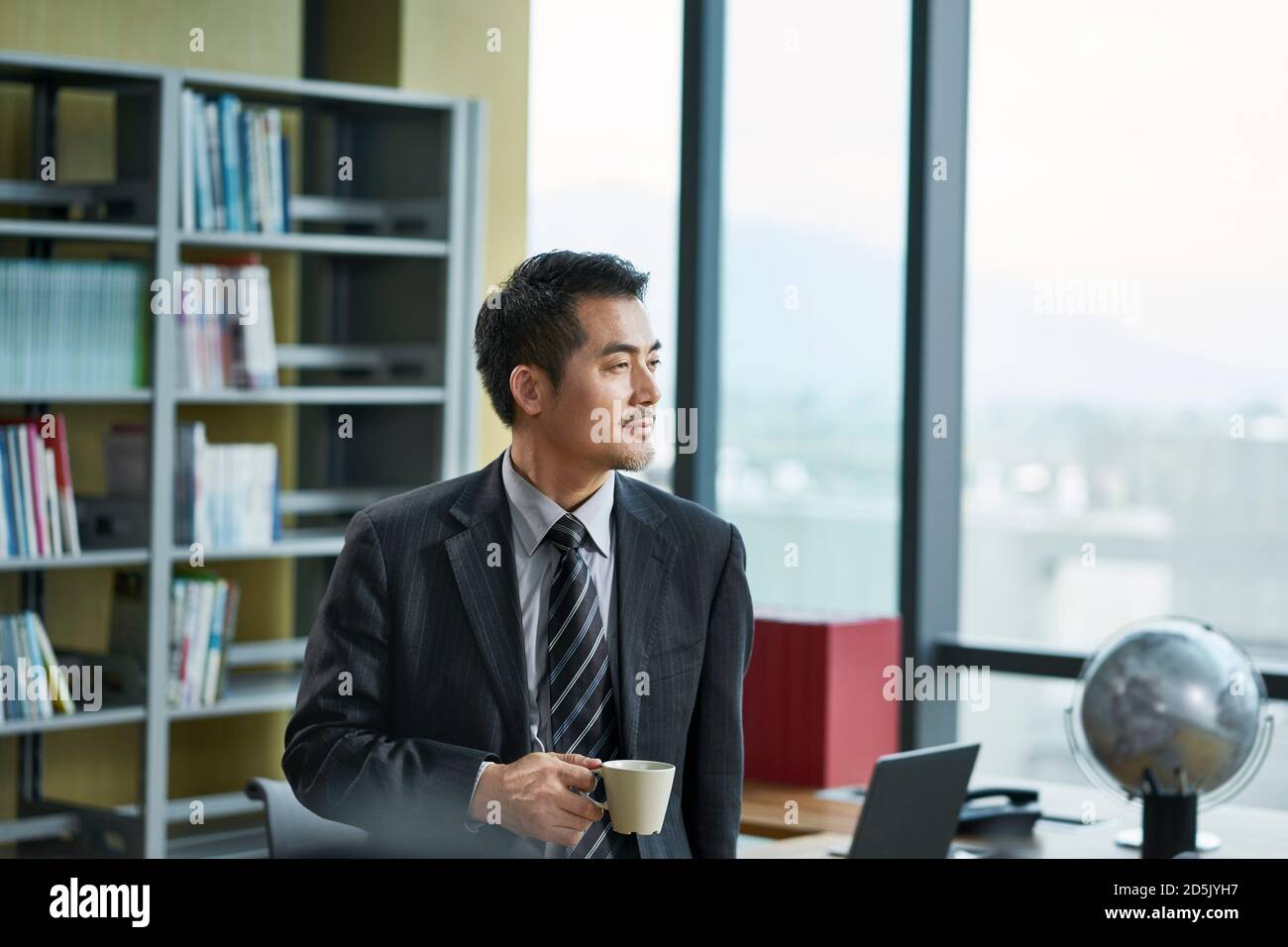 asian corporate executive thinking in office with a cup of coffee in ...