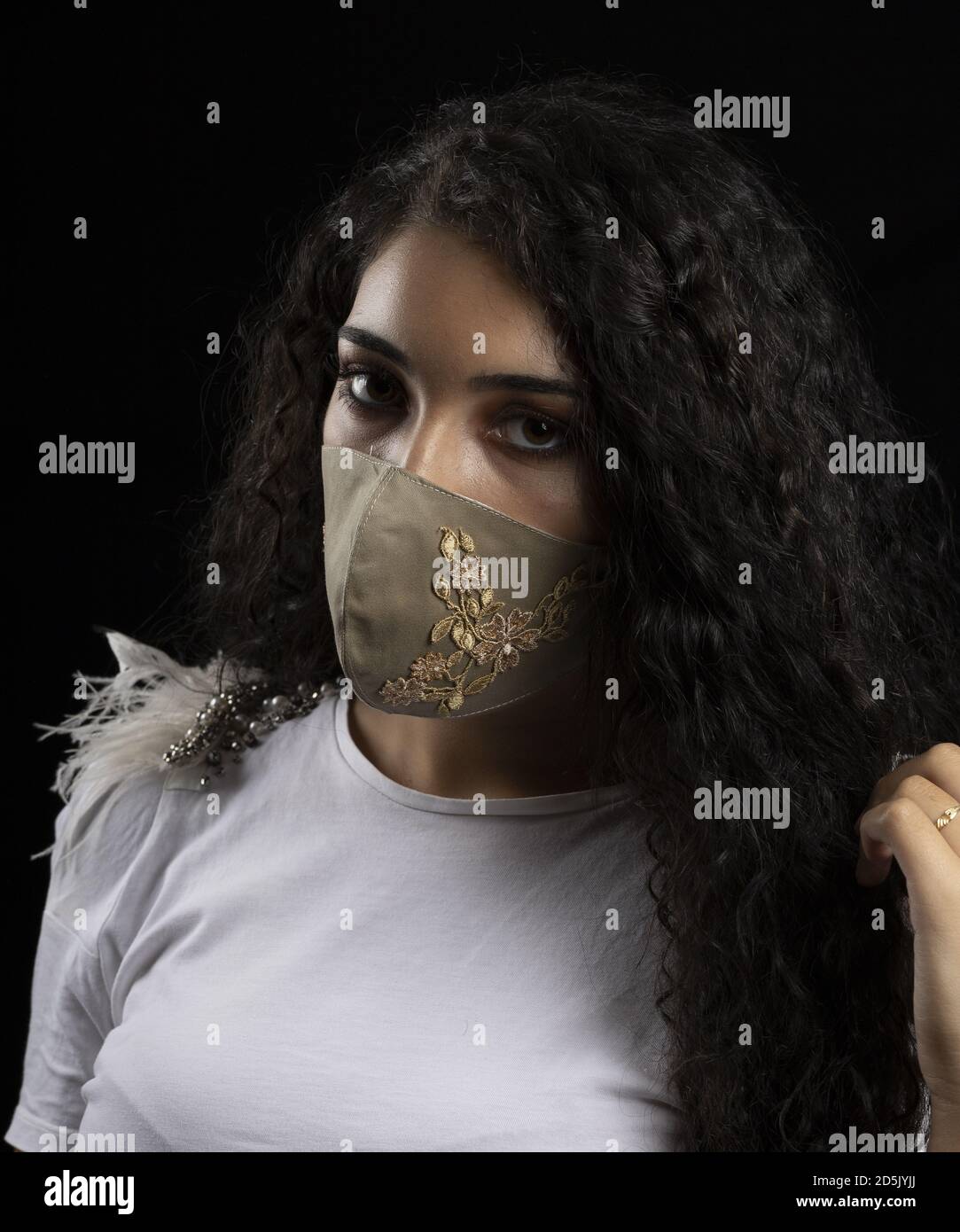 Beautiful Latina wearing a decorative mask on black background - the ...