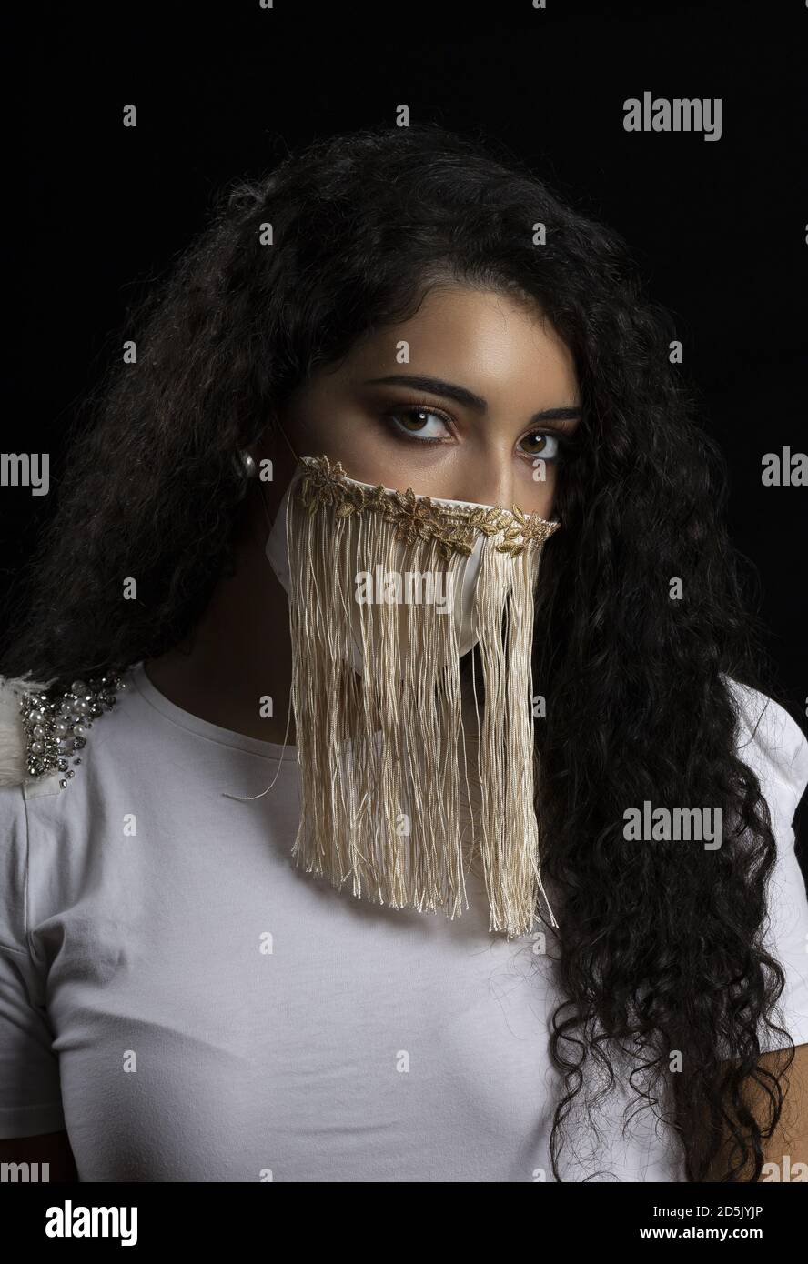 Beautiful Latina wearing a decorative mask on black background - the ...