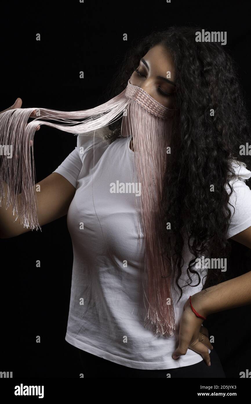 Beautiful Latina wearing a decorative mask on black background - the ...