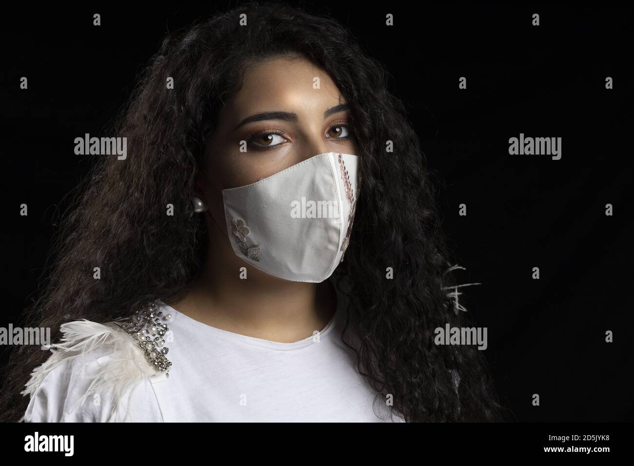 Beautiful Latina wearing a decorative mask on black background - the ...