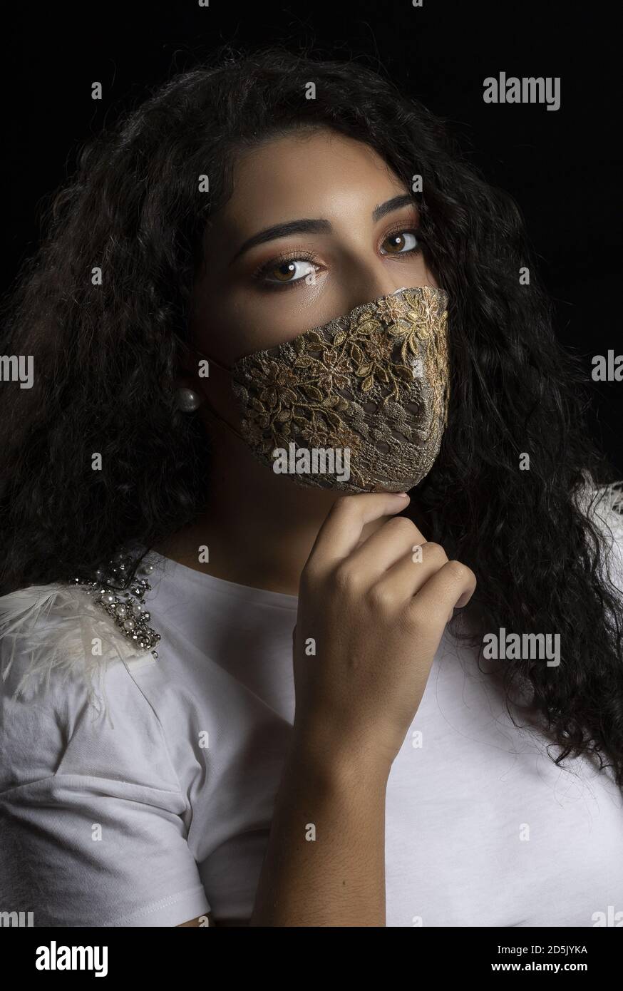 Beautiful Latina wearing a decorative mask on black background - the ...