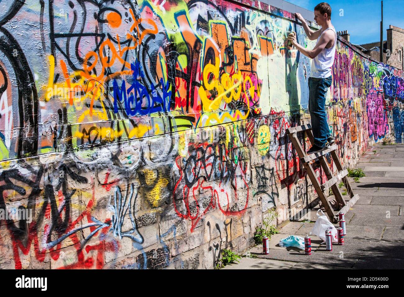 A young man spraying graffiti on a wall Stock Photo - Alamy