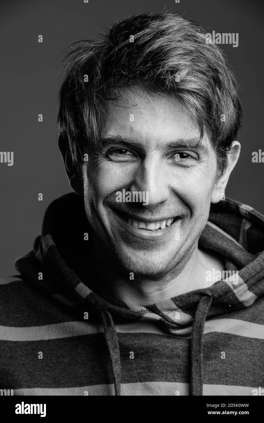 Happy handsome man wearing hoodie against gray background Stock Photo ...