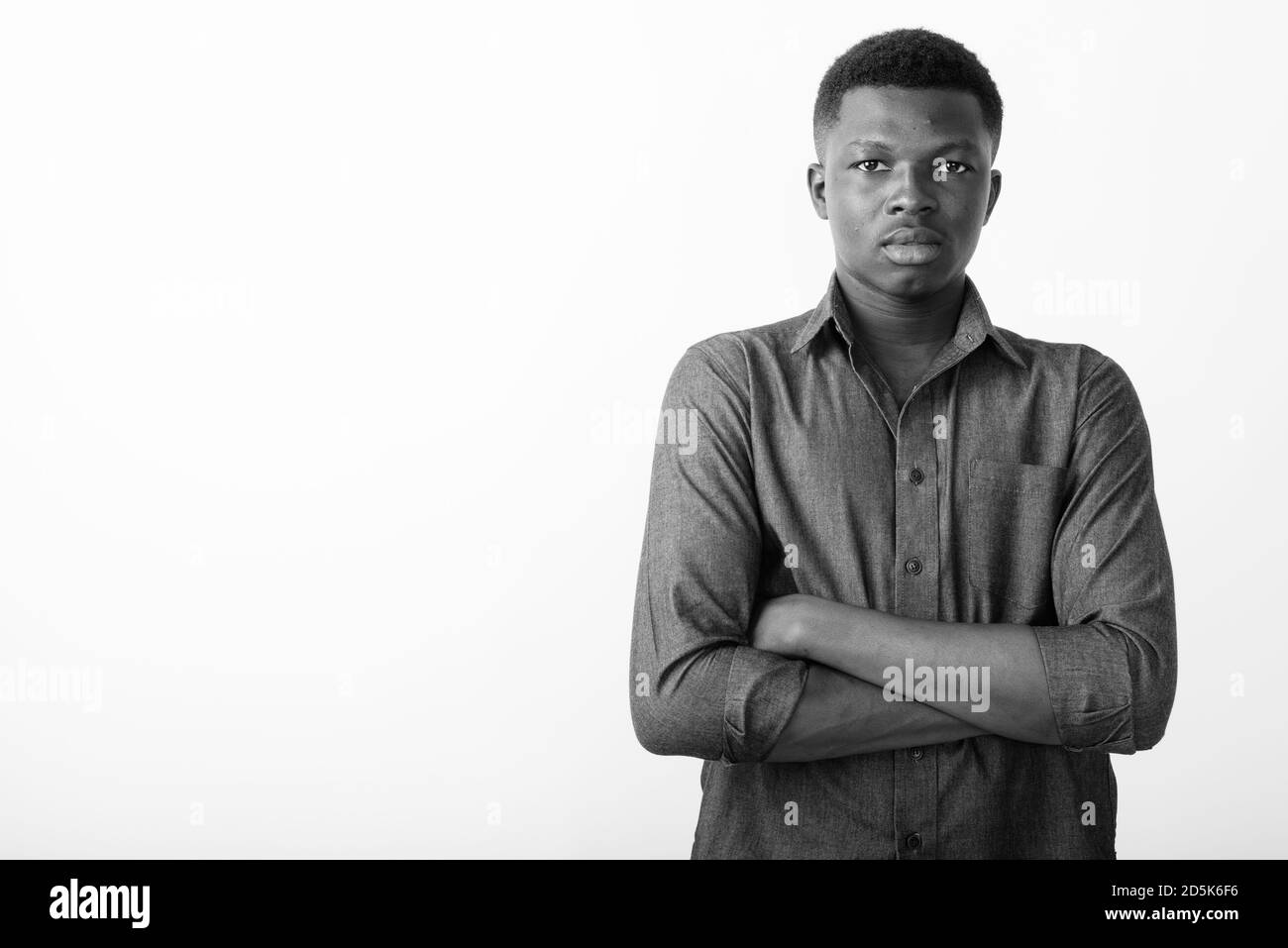 Studio shot of young black African man with arms crossed against white ...