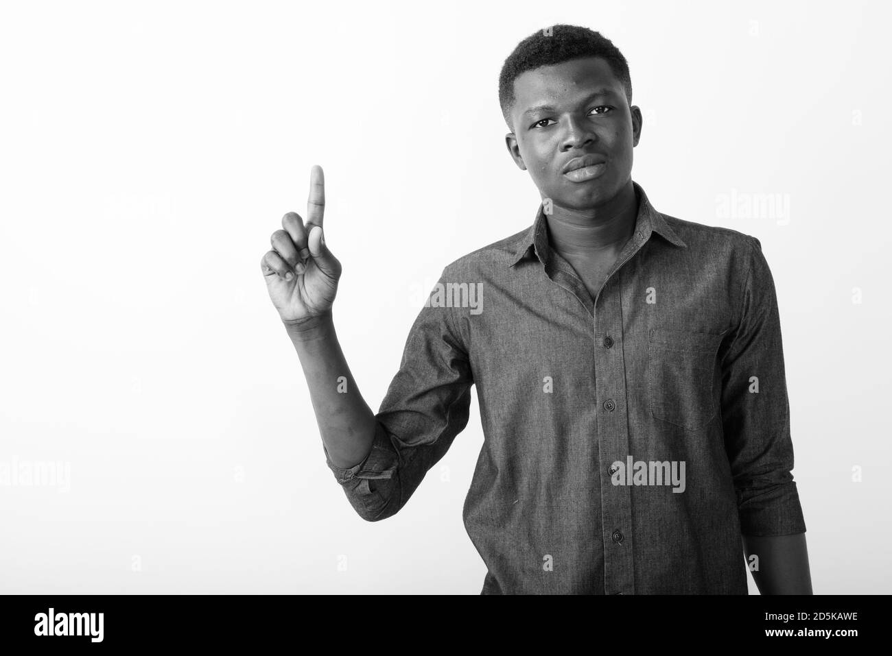 Studio shot of young black African man pointing finger up against white ...