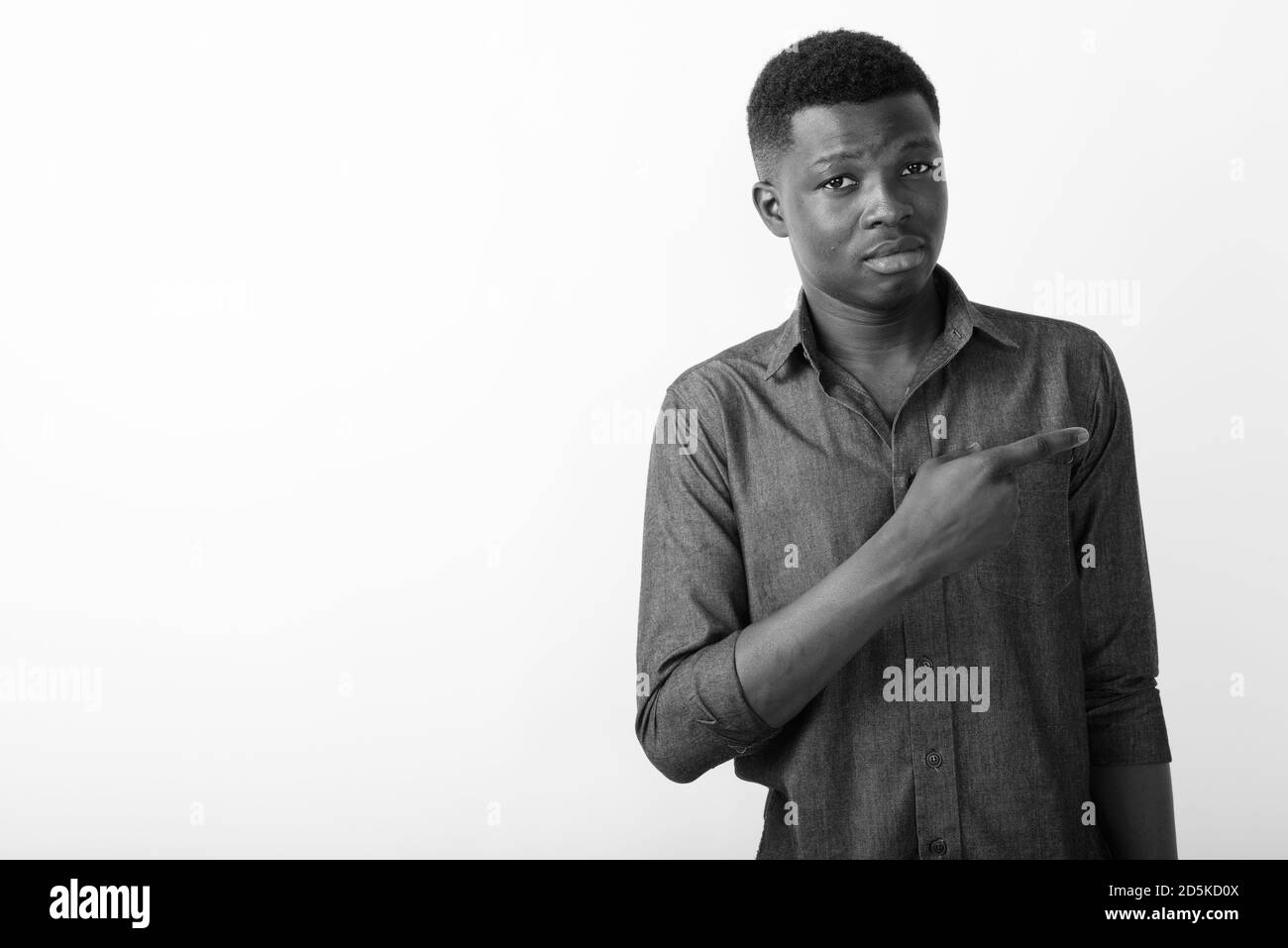 Studio shot of young black African man pointing to the side against ...
