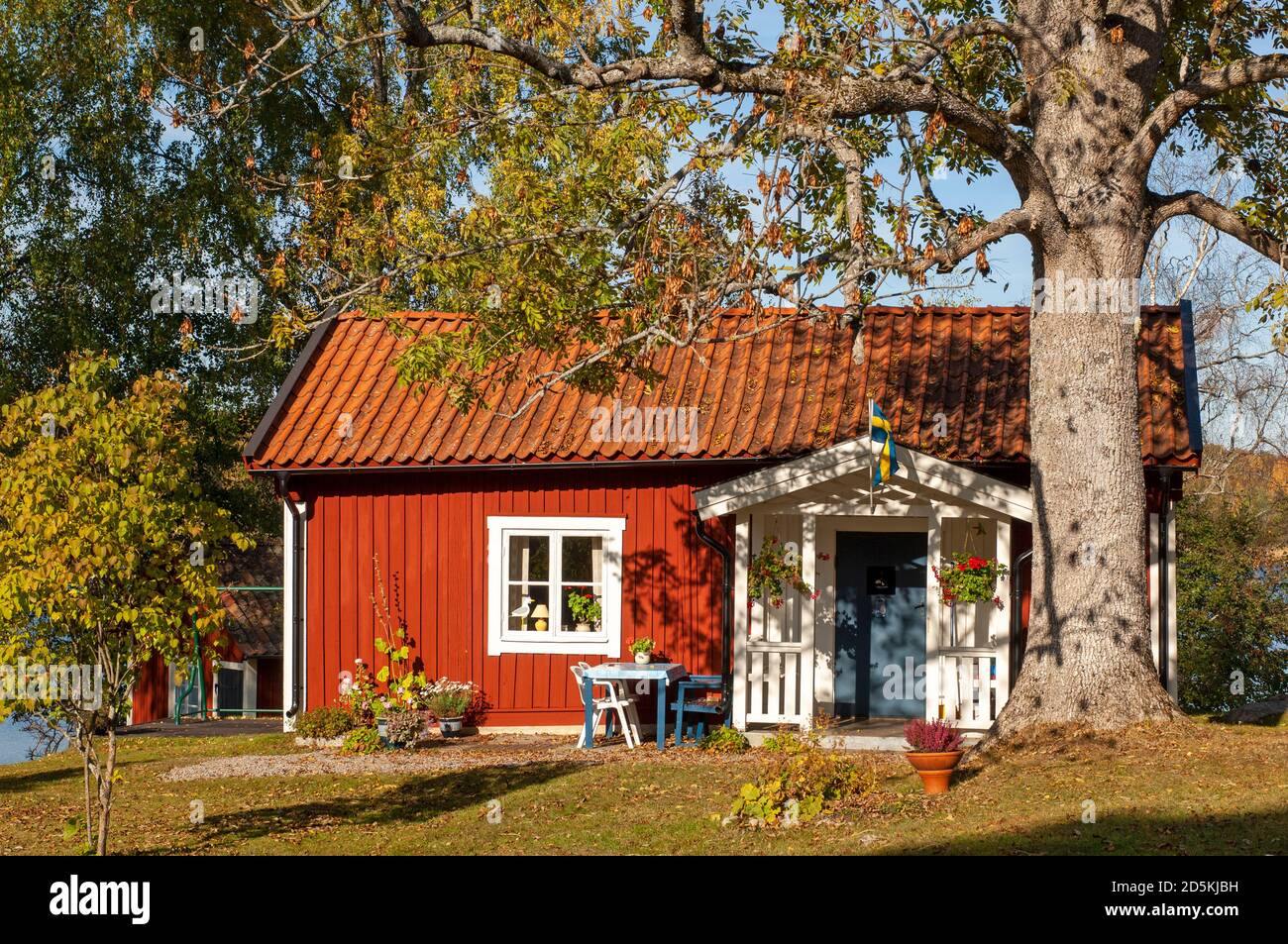A small traditional falu red cottage by a lake Stock Photo - Alamy