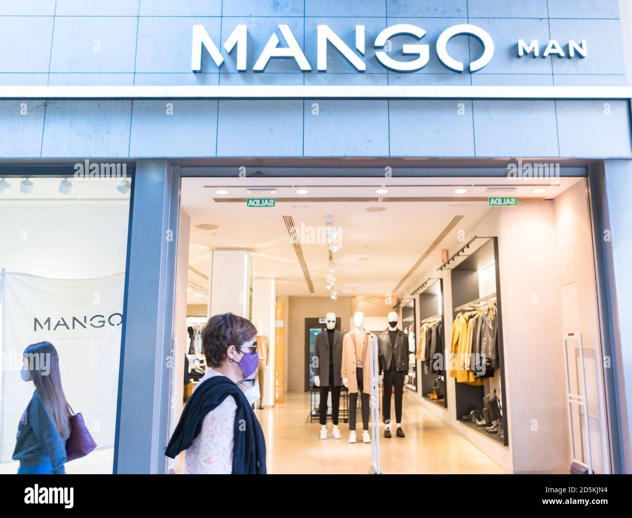 People wearing face masks walk past the Mango Man store Stock Photo - Alamy