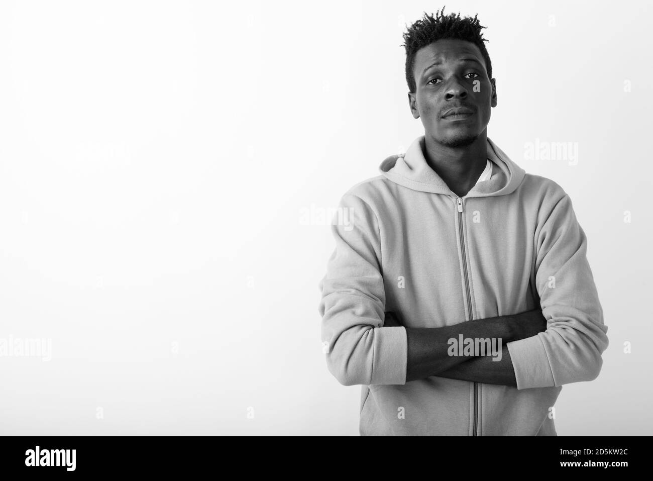 Studio shot of young black African man with arms crossed against white ...