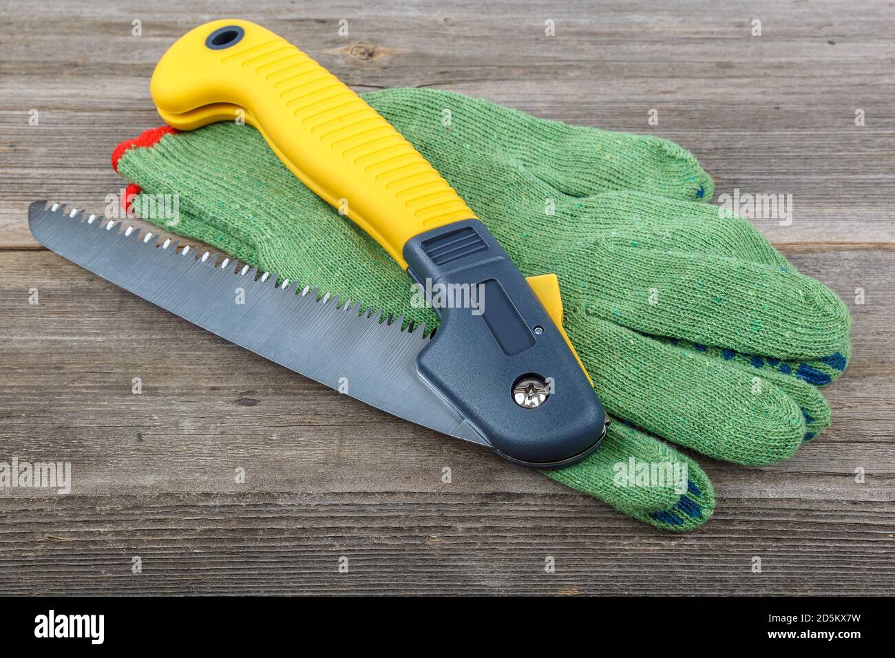 Folding garden saw with work gloves on wooden boards Stock Photo - Alamy