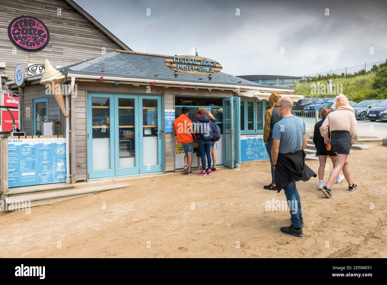 Holidaymakers queueing at the Fistral Beach Pasty Shack as dark clouds ...
