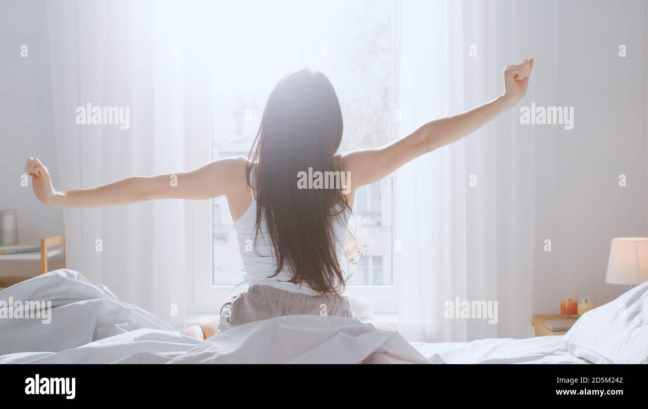 Beautiful Brunette is Waking up in the Morning, Stretches in the Bed ...