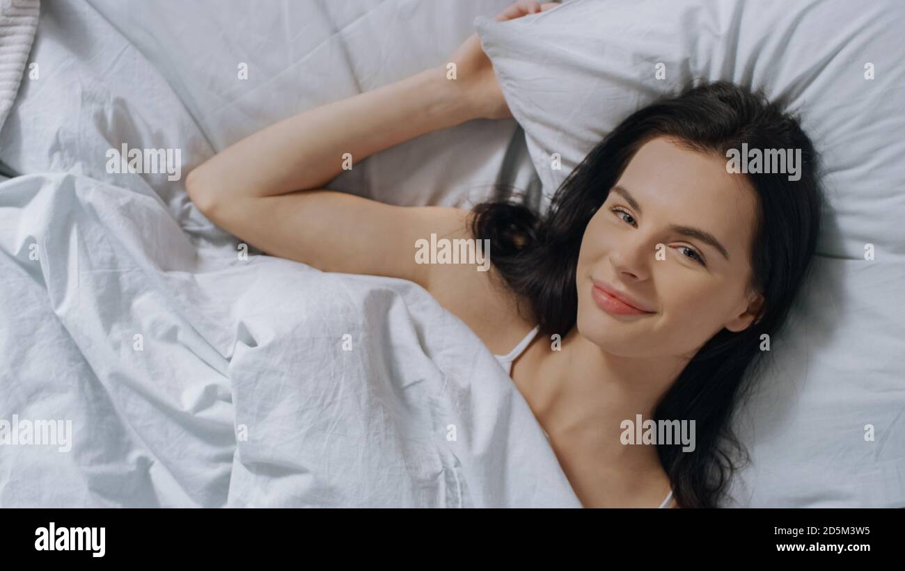 Portrait of Beautiful Young Brunette Charmingly Laying in Her Bed and Sensually Smiling into ...