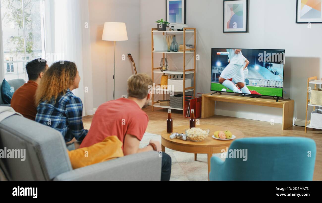 Three Sports Fans Sitting on a Couch in the Living Room Watch Important ...