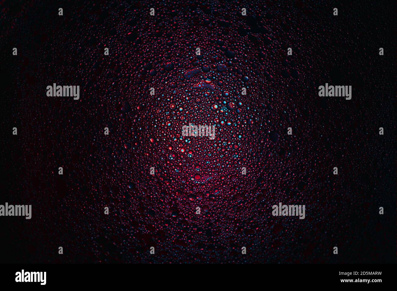 red, blue and purple oil droplets illuminated with colored bulb with ...