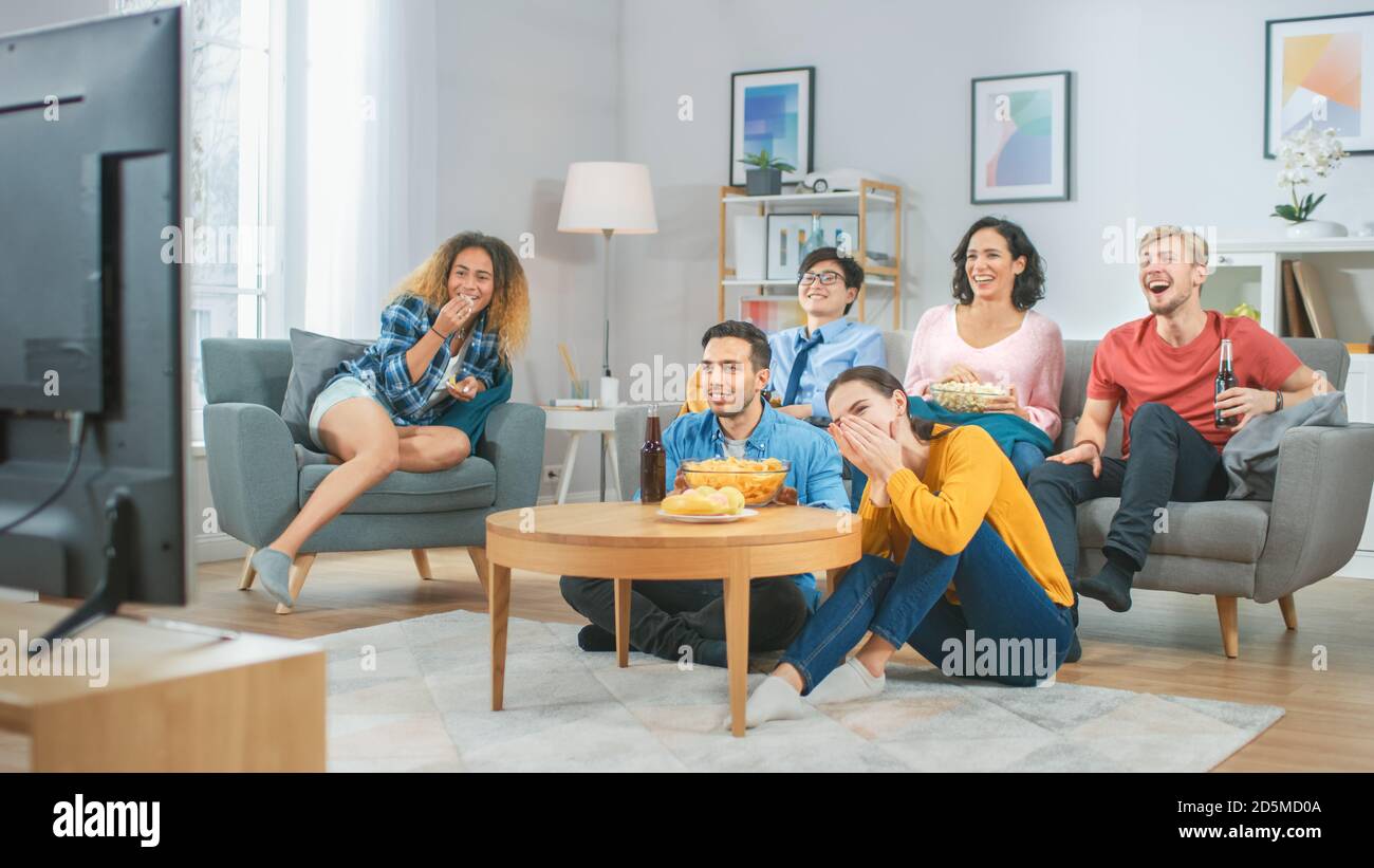 At Home Diverse Group Friends Watching TV Together, Eating Snacks and ...