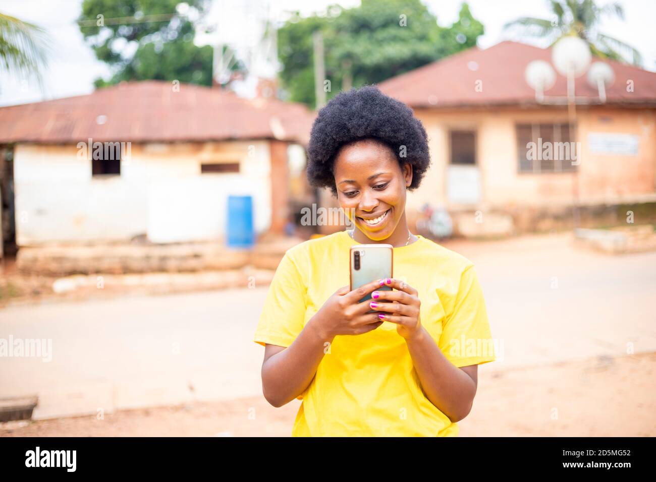 Young black African woman using mobile phone standing outside Stock ...