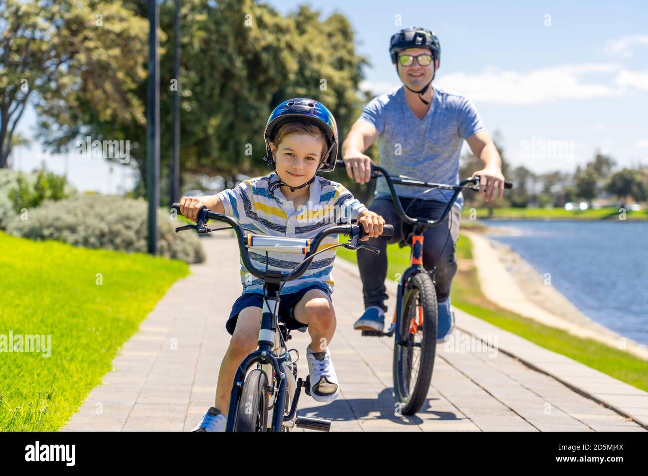 Happy Father and son riding their bicycles by the lake. Father and son ...