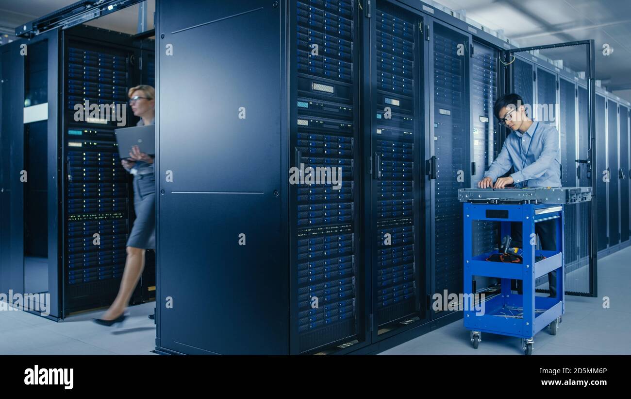 In the Modern Data Center: Team of IT Technicians Working with Server ...
