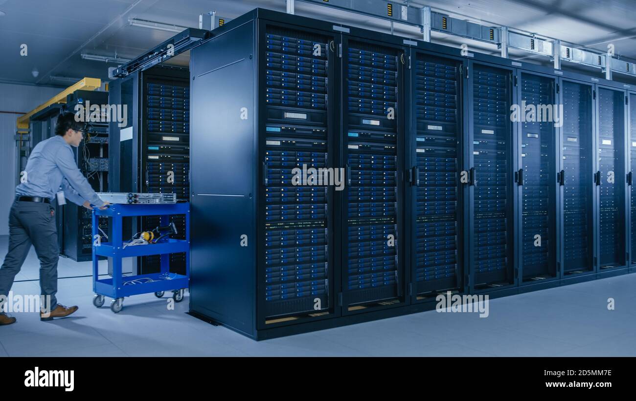 In the Modern Data Center: Team of IT Technicians Working with Server ...