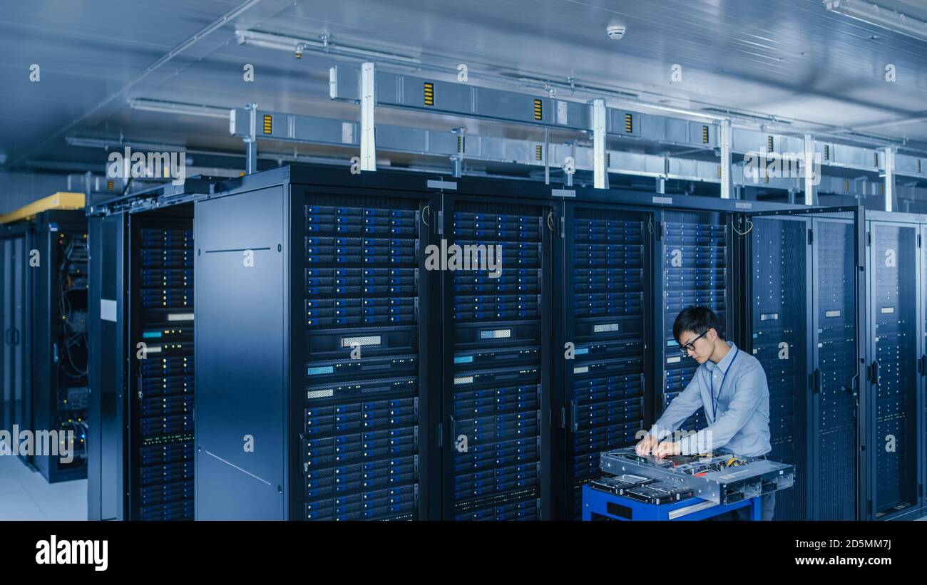 In the Modern Data Center: IT Technician Working with Server Racks, on ...