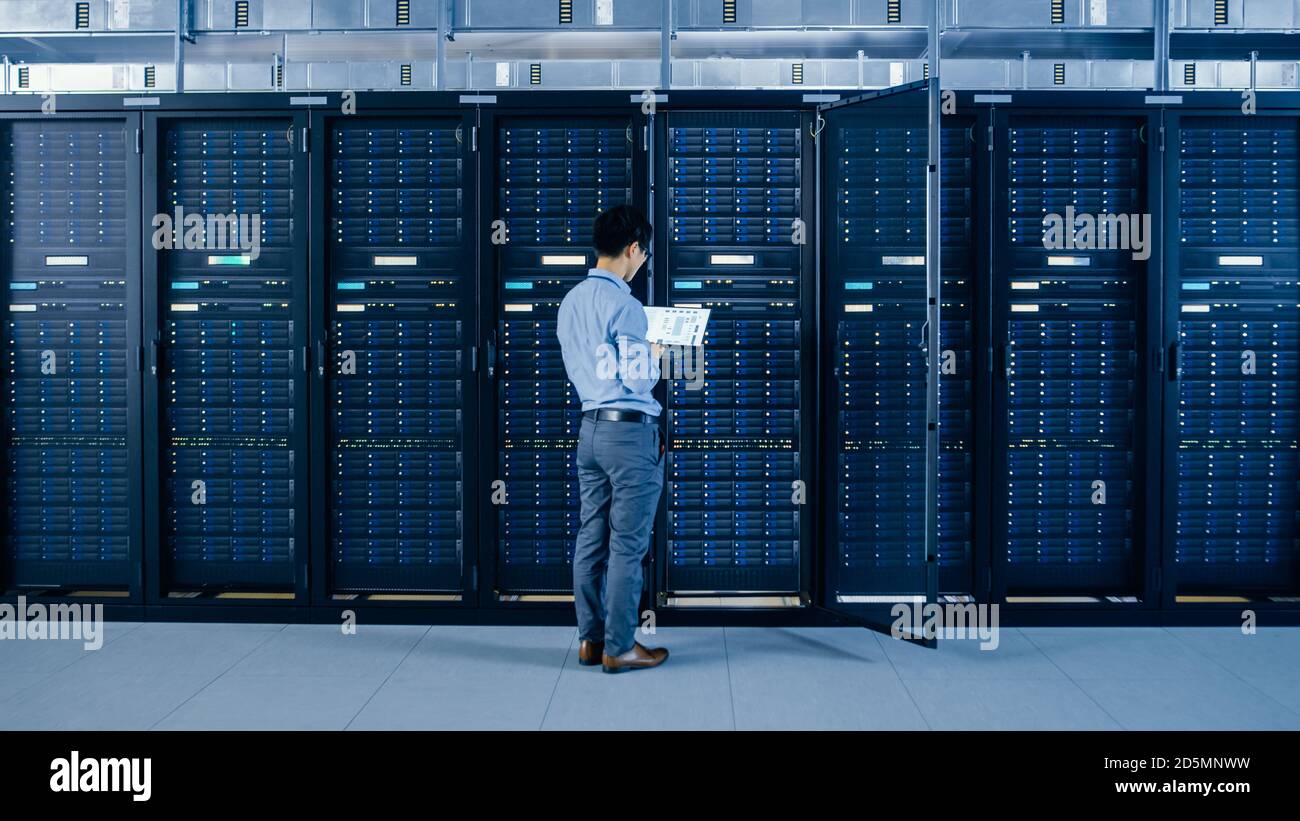In the Modern Data Center: IT Engineer Standing Beside Open Server Rack ...
