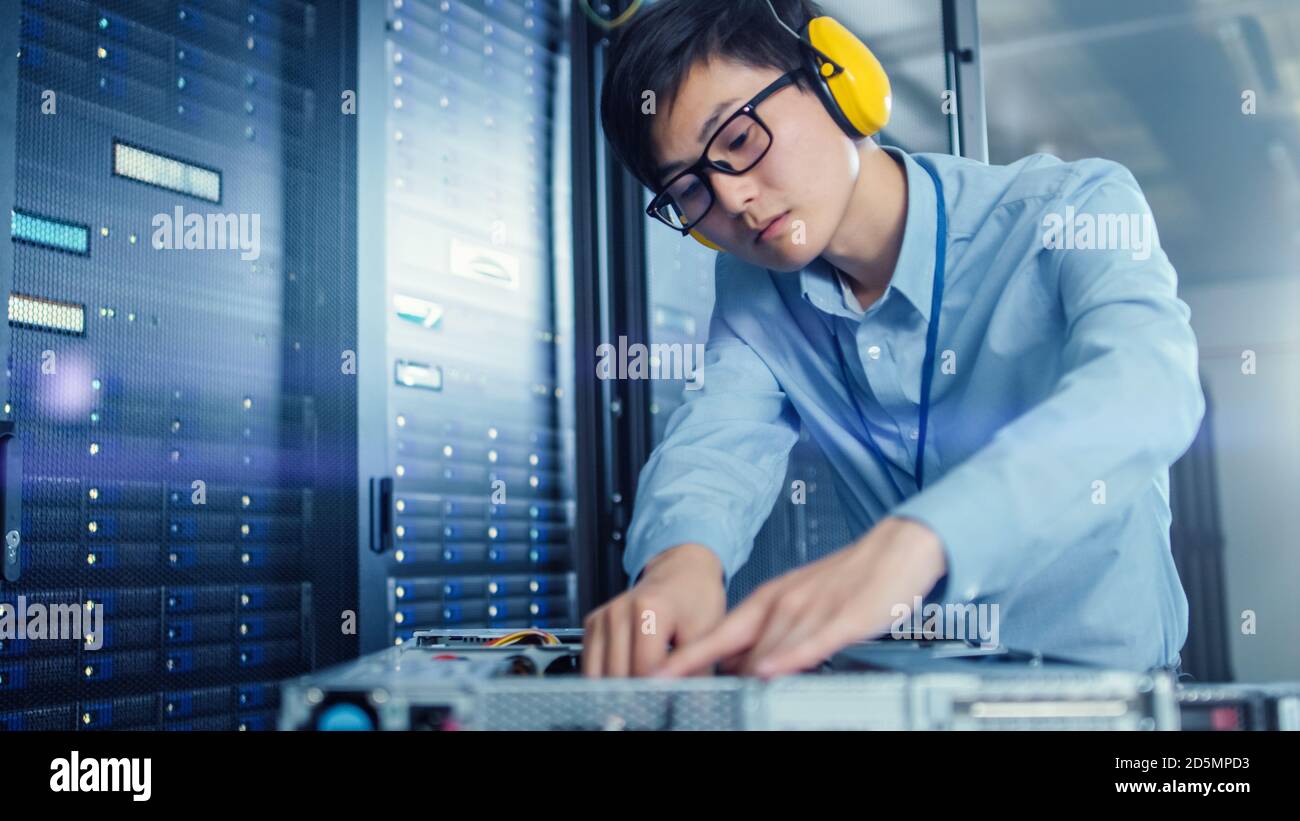 In the Modern Data Center: IT Engineer Wearing Protective Headphones ...