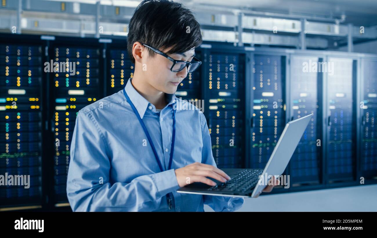 In the Modern Data Center: Portrait of IT Engineer Standing with Server ...