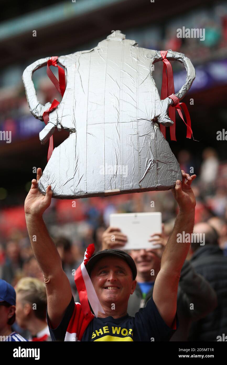 An Arsenal fan in the stands holds up a cardboard cut out trophy Stock ...