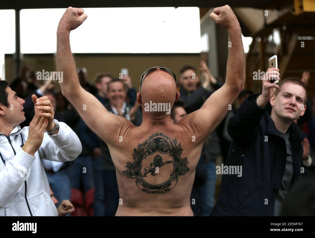 A Millwall fan with a large club tattoo on his back celebrates victory ...