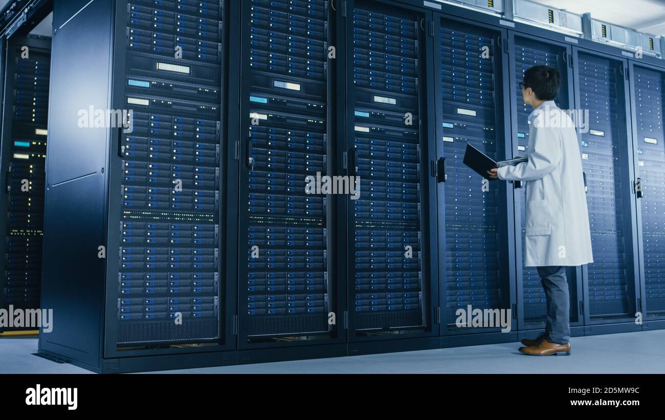 In Data Center: Male IT Specialist Wearing White Coat Stands Beside ...