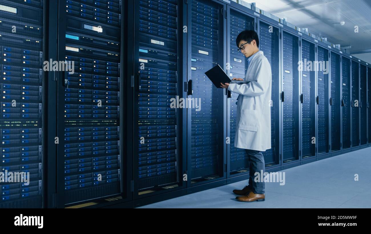 In Data Center: Male IT Specialist Wearing White Coat Stands Beside ...
