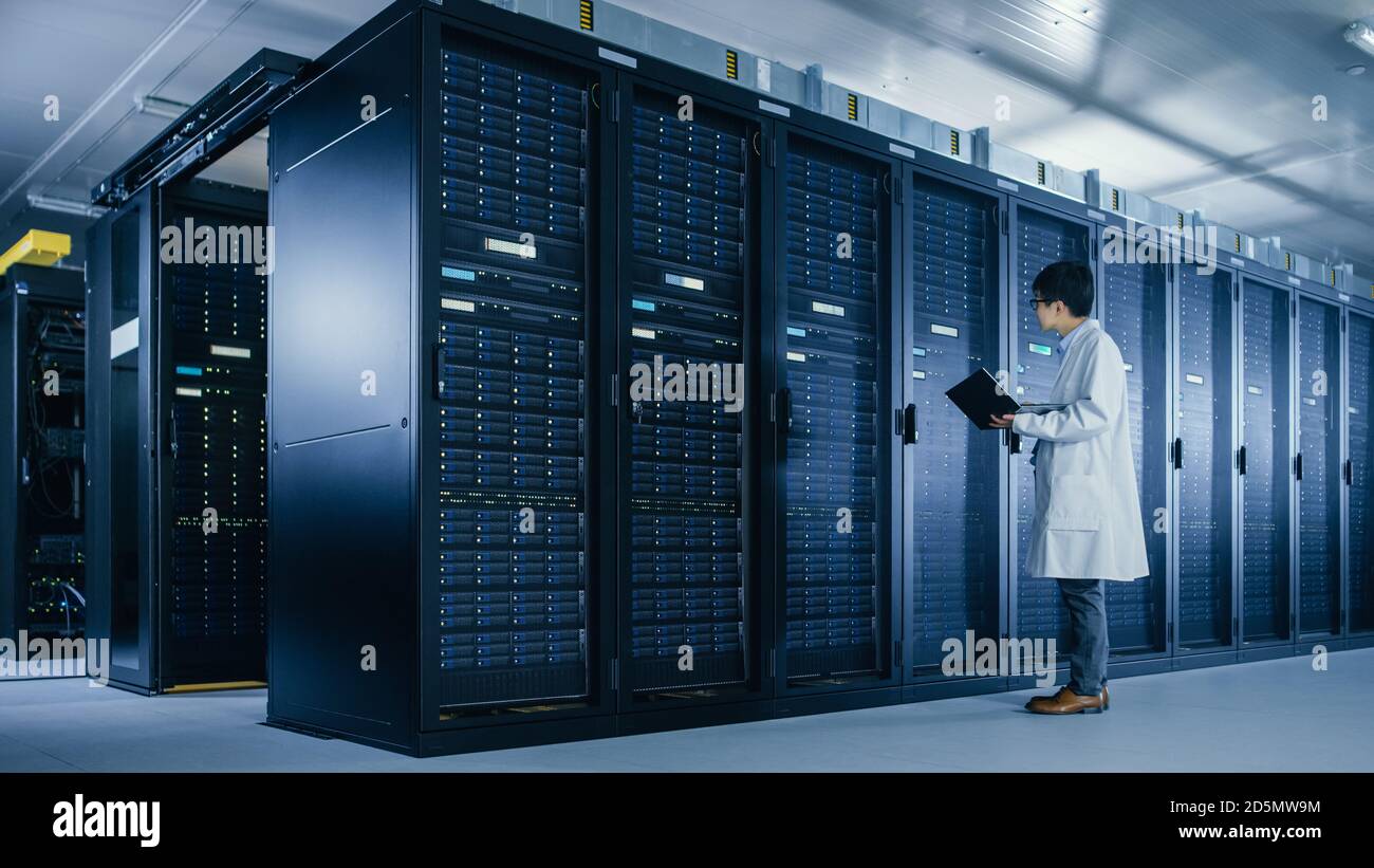 In Data Center: Male IT Specialist Wearing White Coat Stands Beside ...