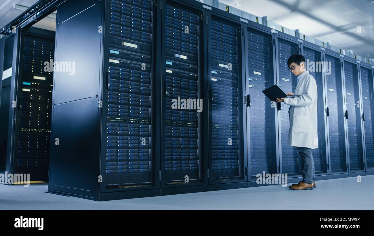 In Data Center: Male IT Specialist Wearing White Coat Stands Beside ...