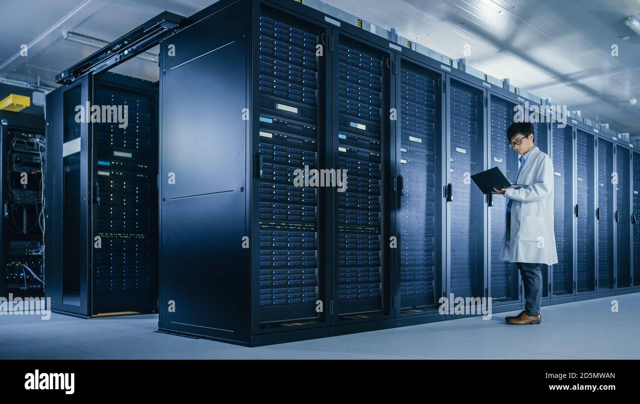 In Data Center: Male IT Specialist Wearing White Coat Stands Beside ...