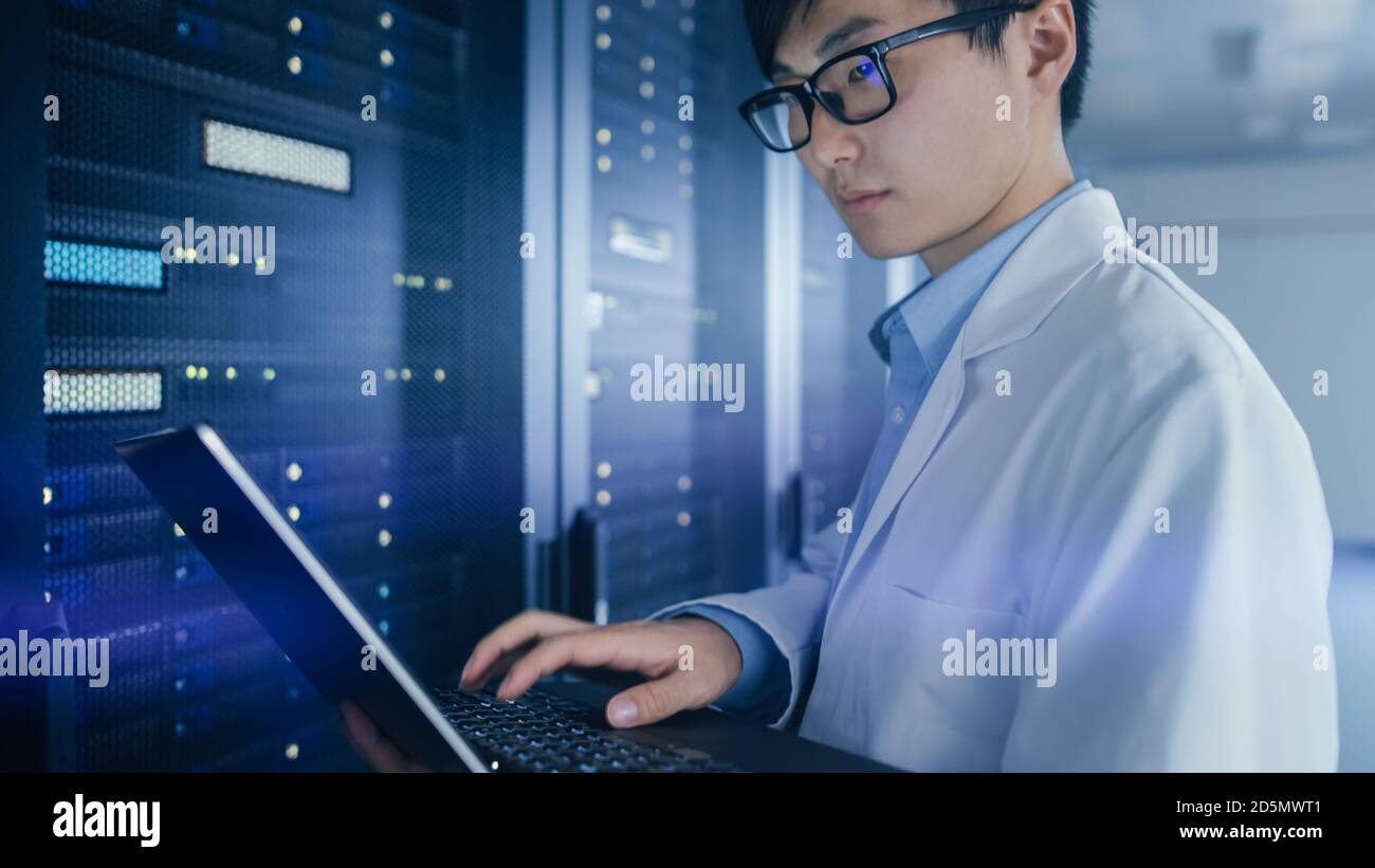 In Data Center: Male IT Specialist Wearing White Coat Stands Beside ...