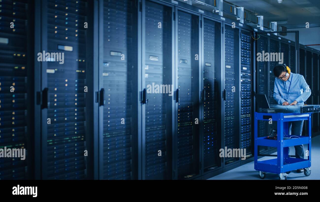 In the Modern Data Center: IT Technician Wearing Protective Headphones ...